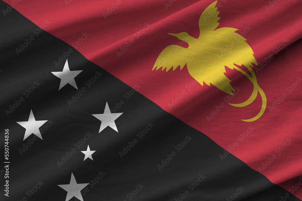 Papua New Guinea flag with big folds waving close up under the studio ...