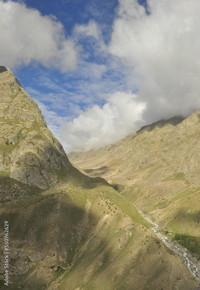 Dry mountains covered with clouds from peak, flowing water from top of ...