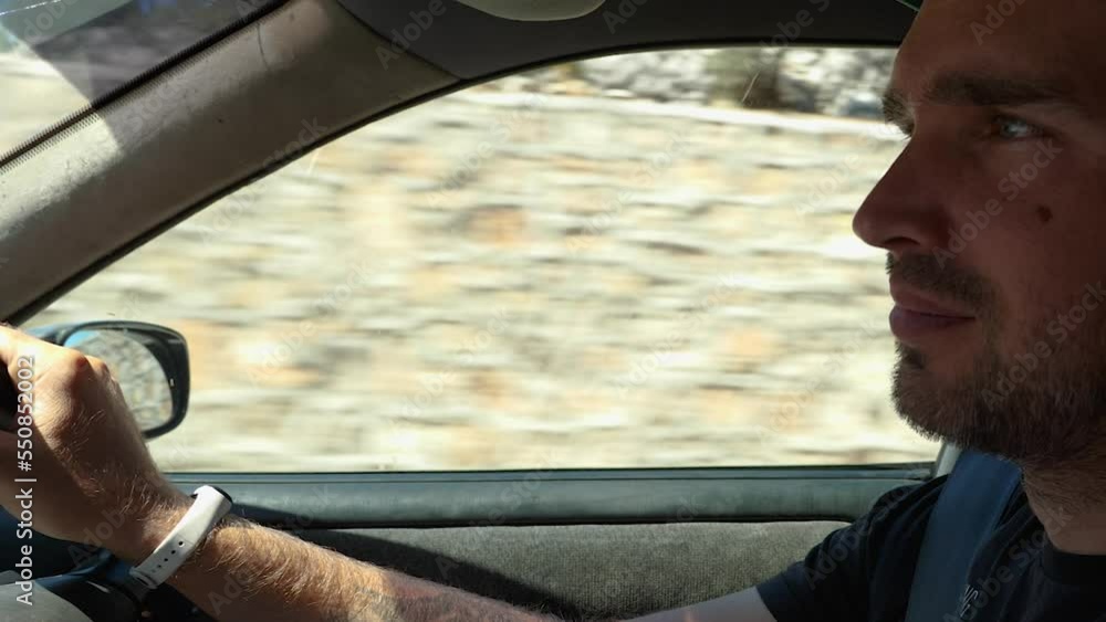 Close-up of a smiling bearded Caucasian man behind the wheel of a car ...