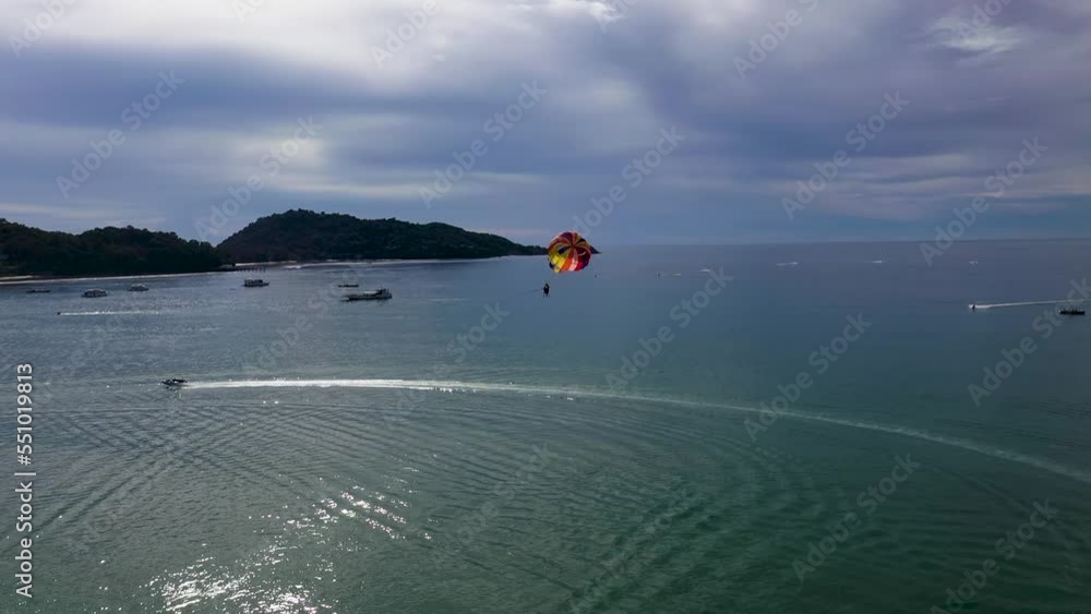 Parasailing in Phuket. A long shot of a man flying in the sky with help ...