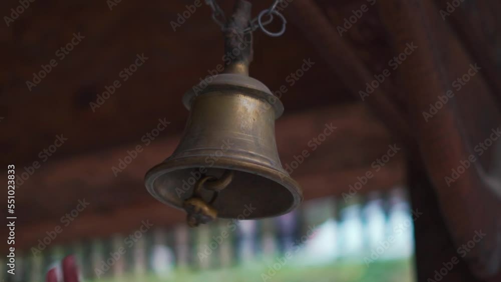 Closeup shot of hand of an Indian man ringing the temple bell inside ...