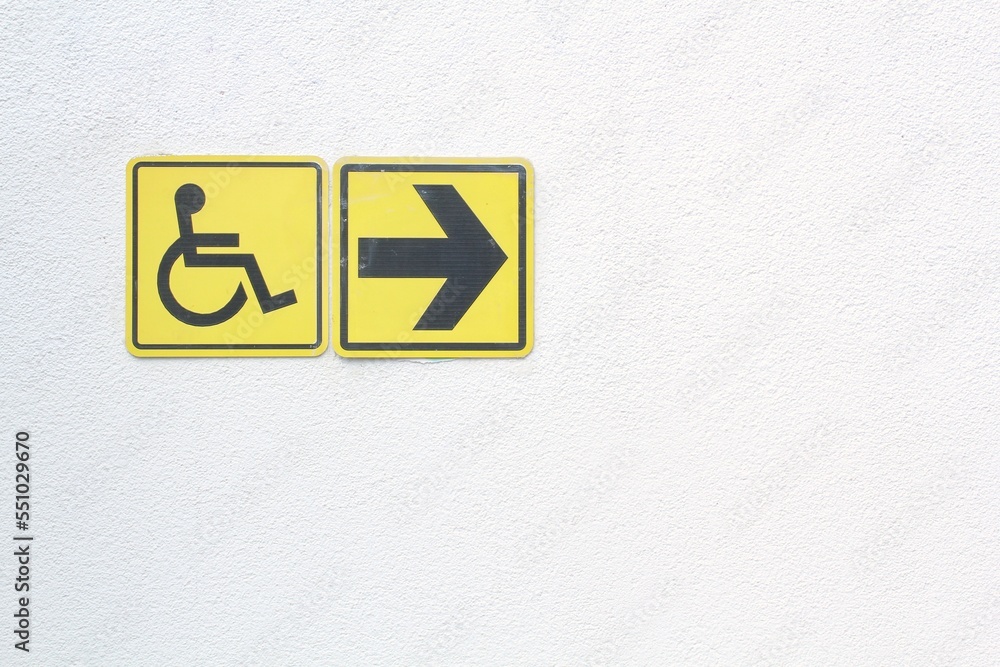 Yellow disabled sign and arrow right pointing sign on white background ...