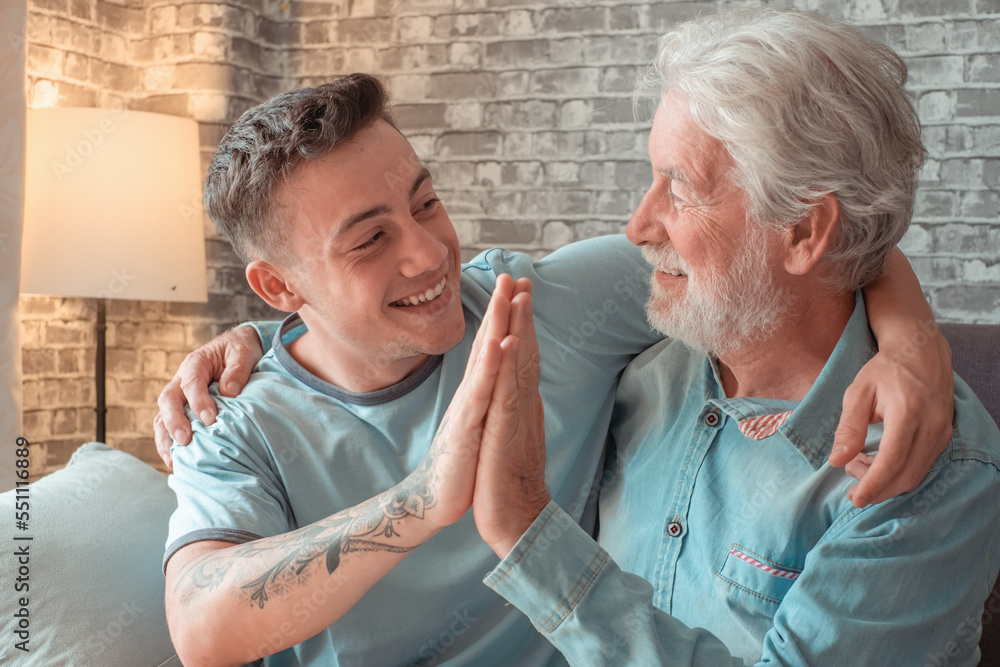 Young boy and his grandfather smile as they high five each other while ...