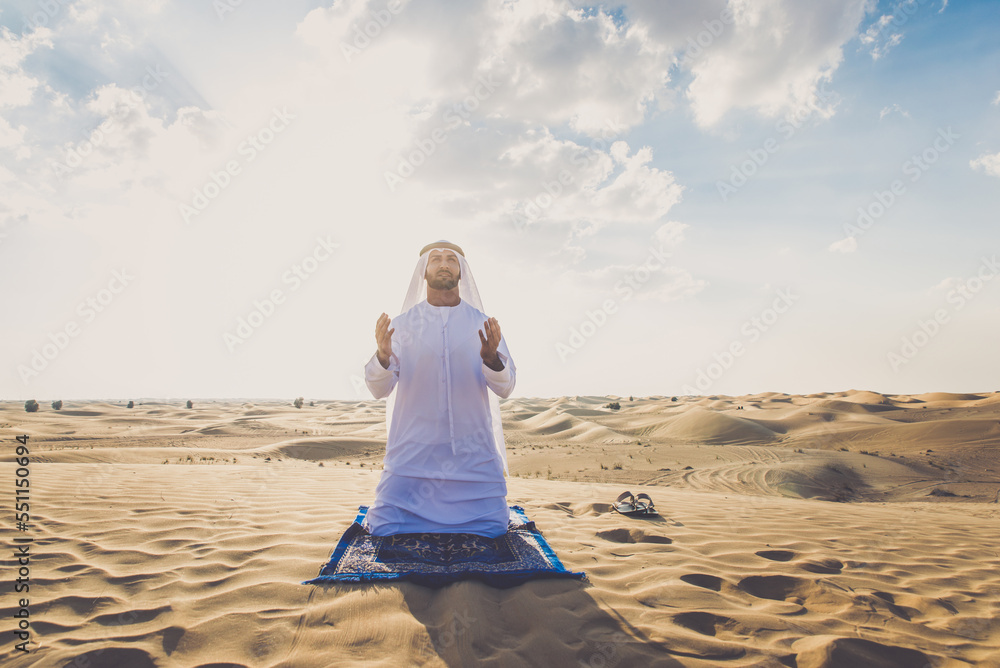 Arab man wearing typical middle eastern clothing in the desert praying ...