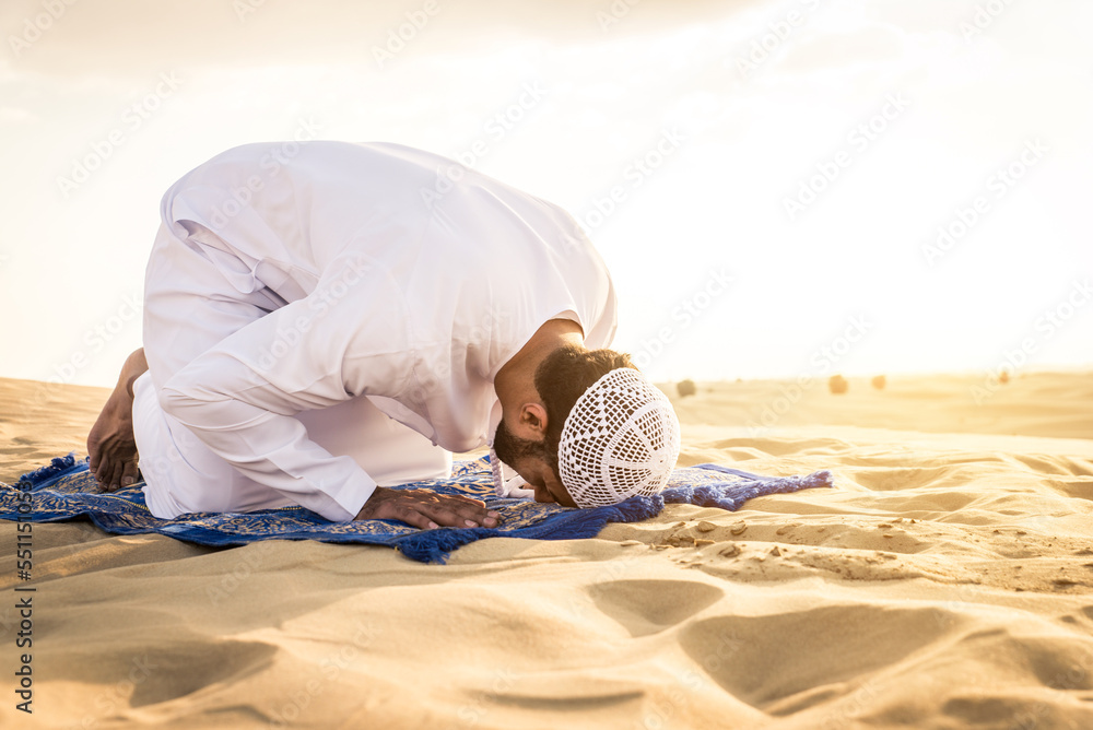 Arab man wearing typical middle eastern clothing in the desert praying ...