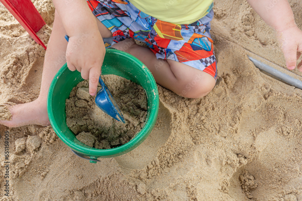 child digging hole in clean beach sand during sunny day with family ...