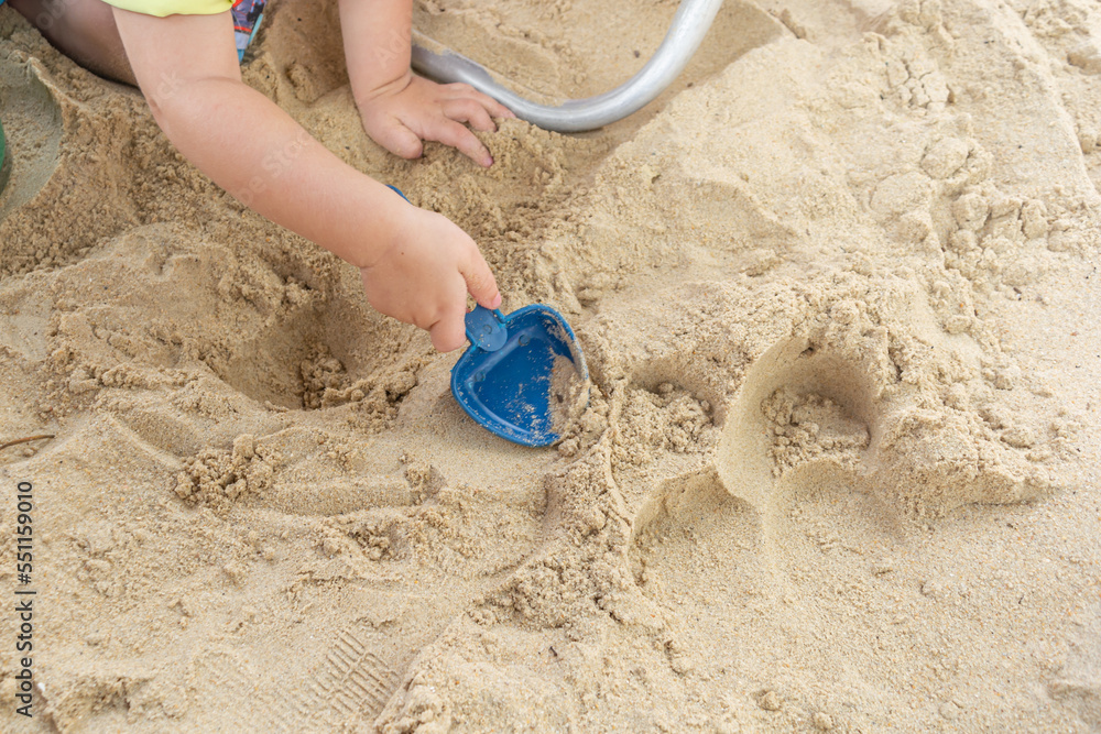 child digging hole in clean beach sand during sunny day with family ...