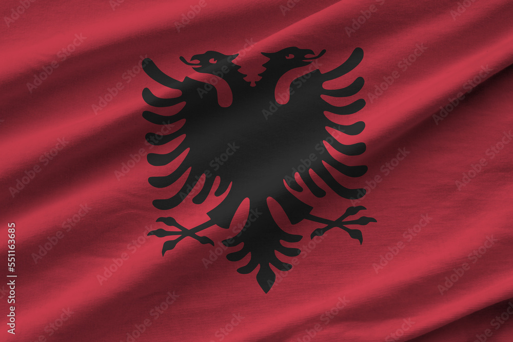 Albania flag with big folds waving close up under the studio light ...