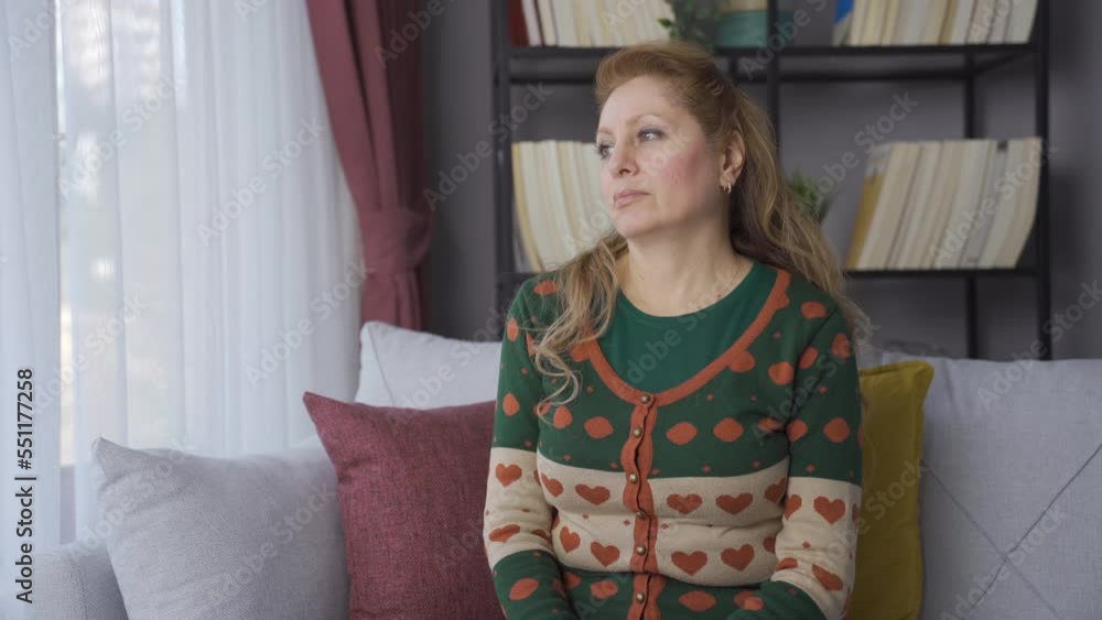 Thoughtful mature woman looking out the window at home questioning old ...