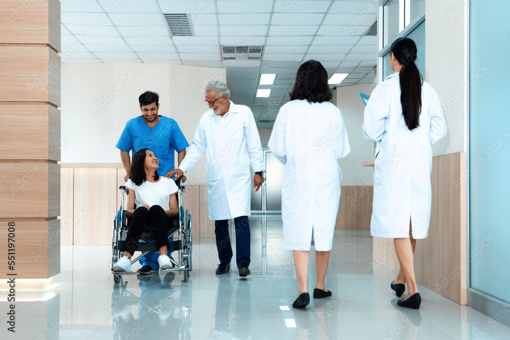Doctor and male nurse transport a female patient in a wheelchair along ...