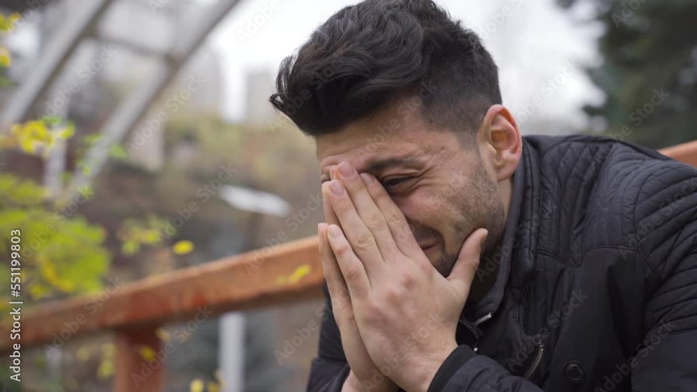 Sadness, loneliness. The young man is crying outdoors and his nerves ...