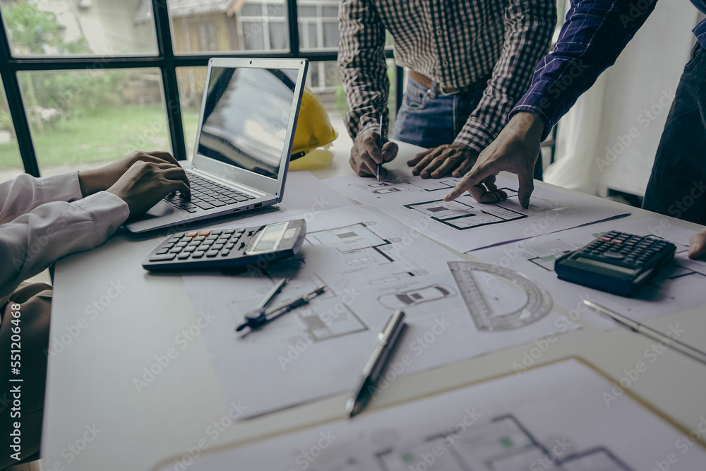 Engineering team meeting for colleagues discussing and reviewing blueprints at desk in office ...