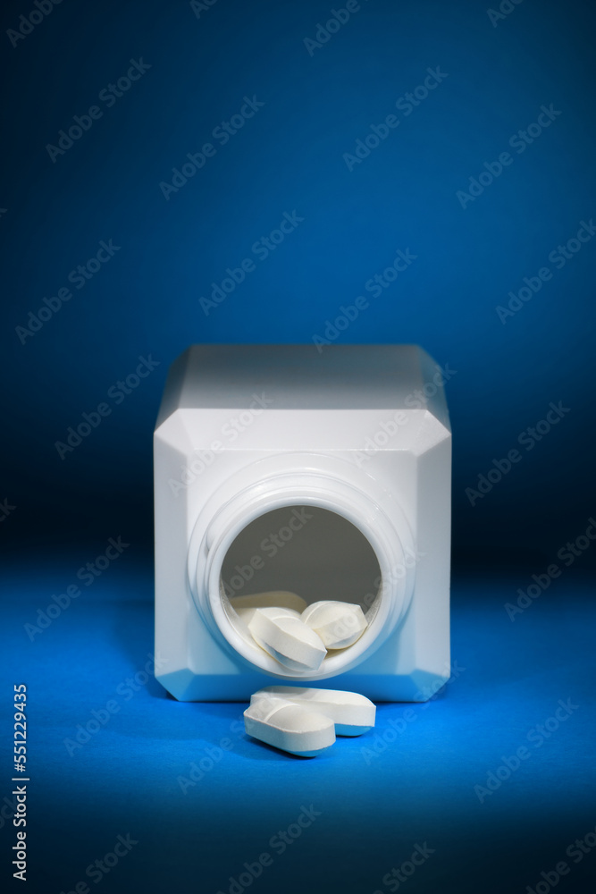 A white, open prescription medication container with some tablets out ...
