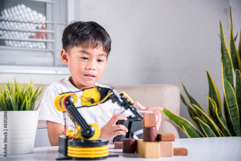 Happy Asian little kid boy using remote control playing robotic machine ...