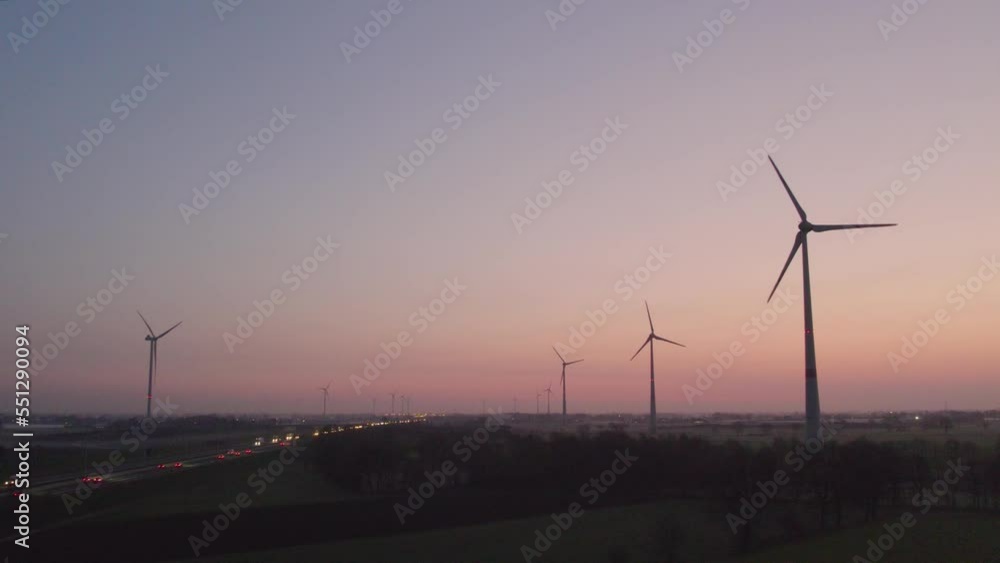 Aerial shot by a drone of windmills with rotating wings among green ...