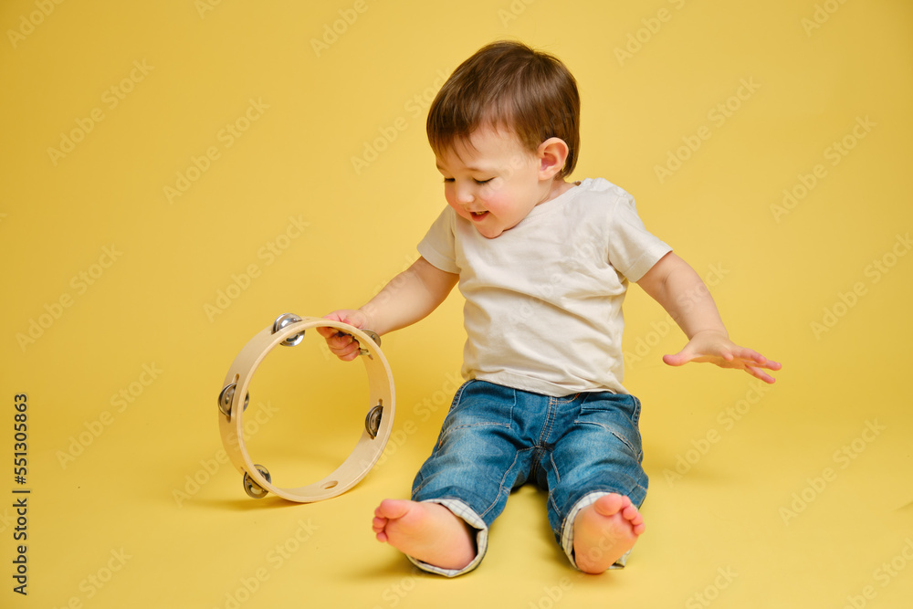 Toddler baby plays the tambourine, a child with a percussion musical ...