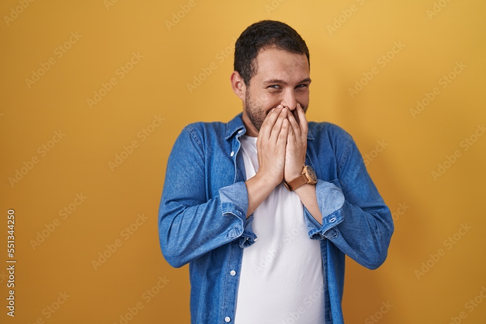 Hispanic man standing over yellow background laughing and embarrassed ...