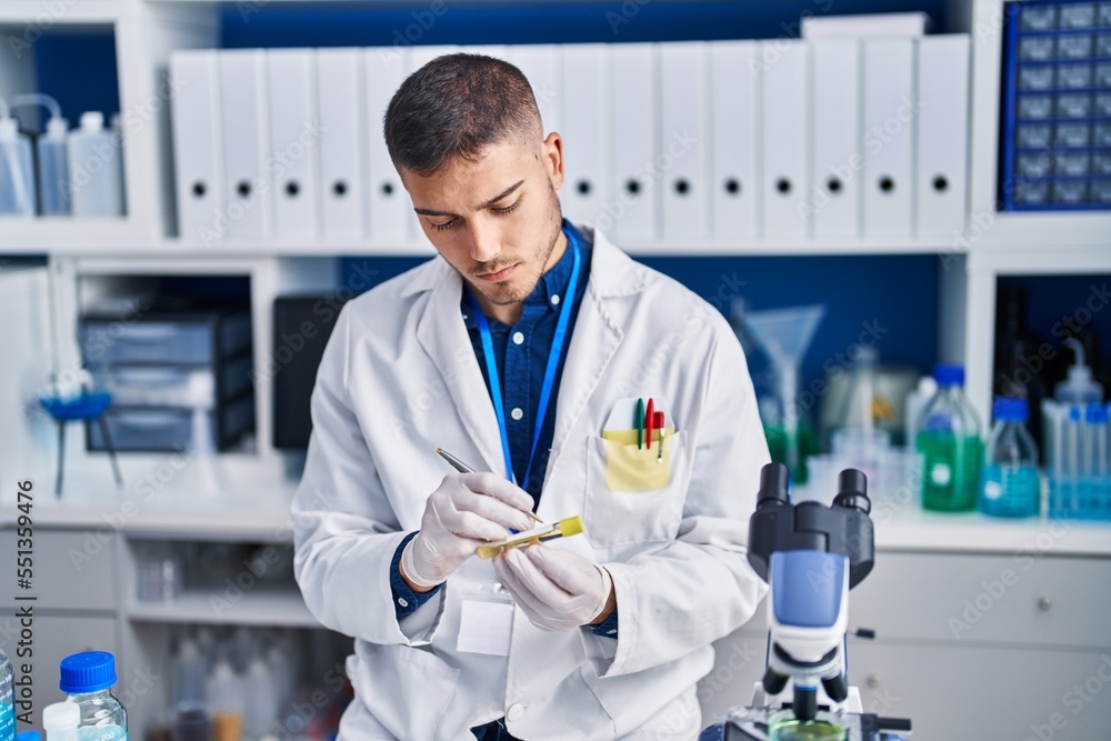 Young hispanic man scientist writing on test tube at laboratory Stock ...