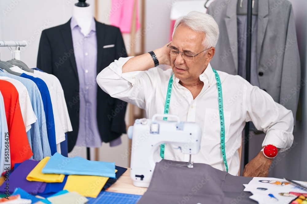 Middle age man with grey hair dressmaker using sewing machine suffering ...