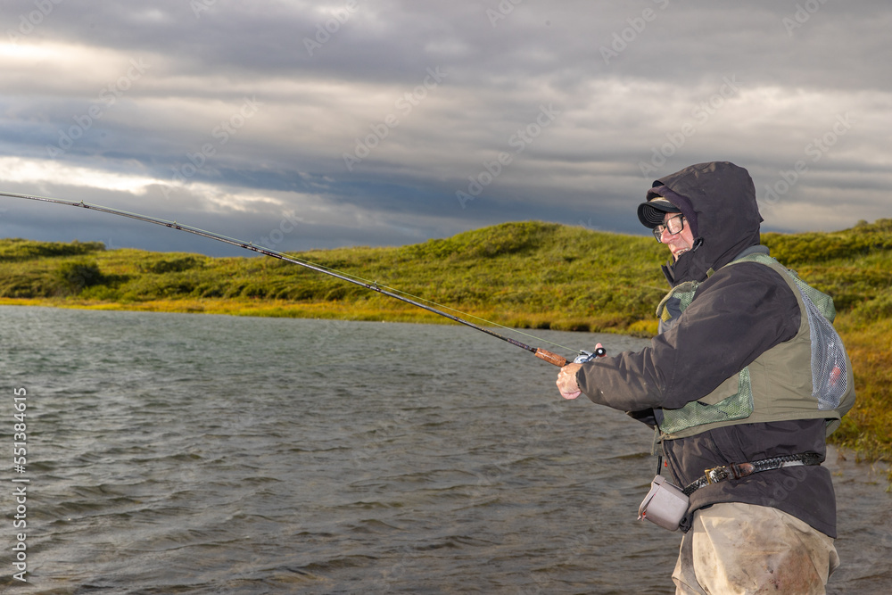 Happy fisherman reels in a coho salmon fish from the Egegik river in ...
