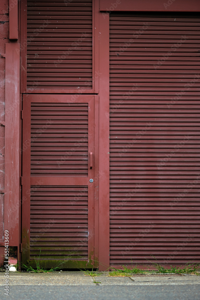 Building facade. Abstract, locked metal door and security shutter to a ...