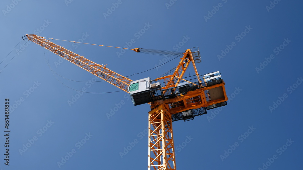 Yellow tower crane luffing boom soars isolated into blue sky Stock ...