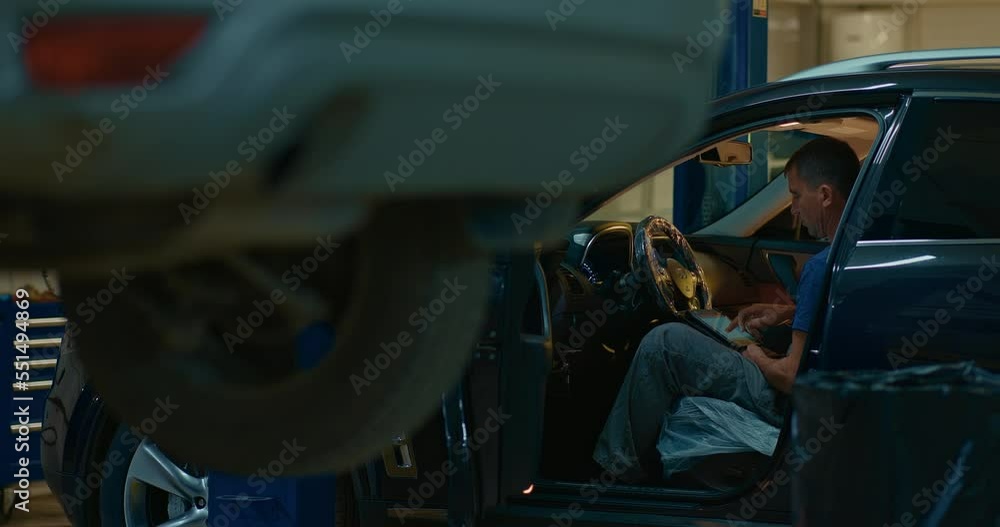 Auto mechanic who uses a computer diagnostic program during the repair ...