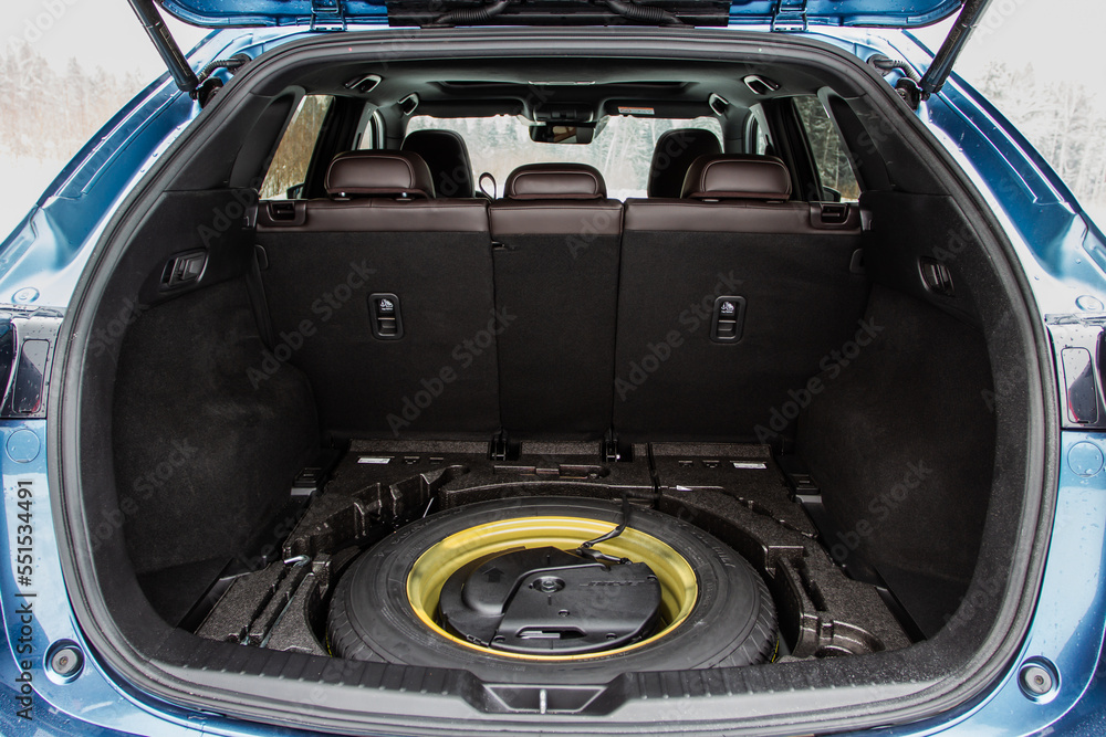 Spare wheel in the trunk of a modern car. Jack lifting and a spare tire ...
