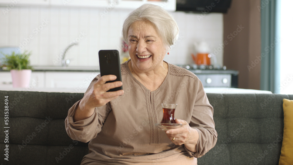 Happy old grandmother holding a mobile phone, having a video call with ...