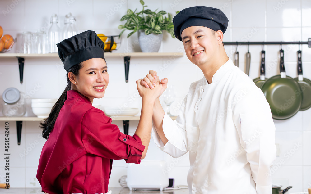 Two young Asian professional couple chefs wearing uniform, hat, happily ...