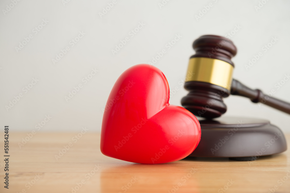 Red heart with hammer judge gavel on wooden office table and white wall ...