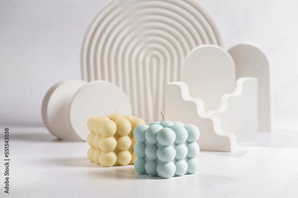 an off-white and blue bubble candle in front of white props for product ...