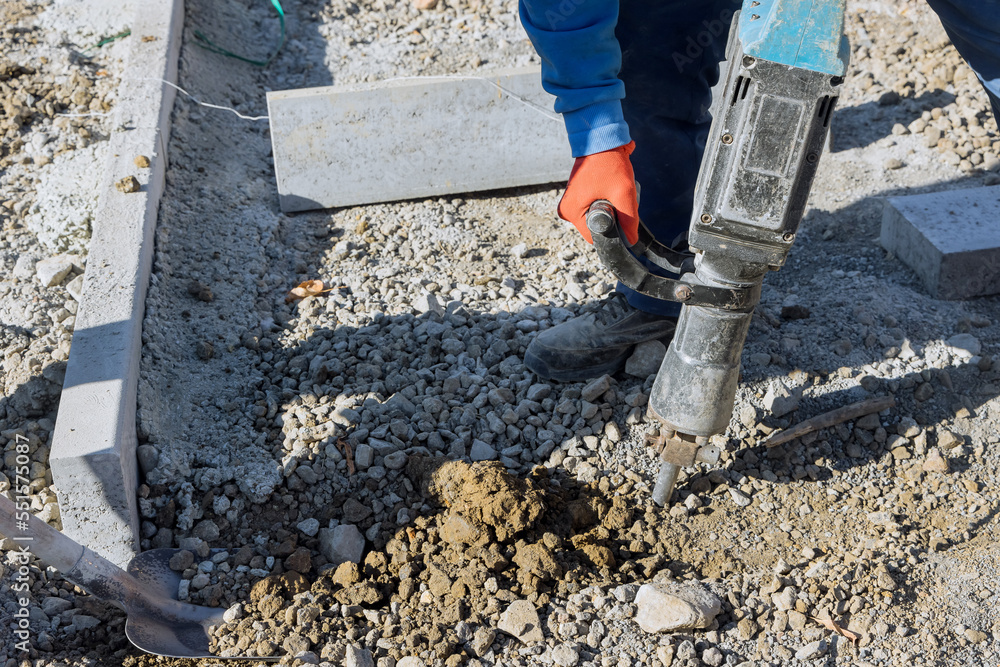 Worker digging and drilling concrete surfaces using jackhammer as part ...