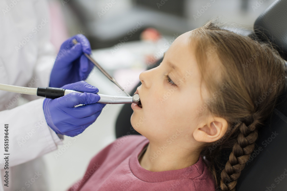Closeup view of cute little girl lying on dentist chair with open mouth ...