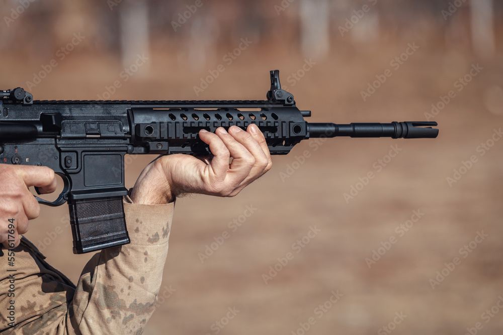 Soldier holding an infantry automatic rifle and aiming. Rifle with ...
