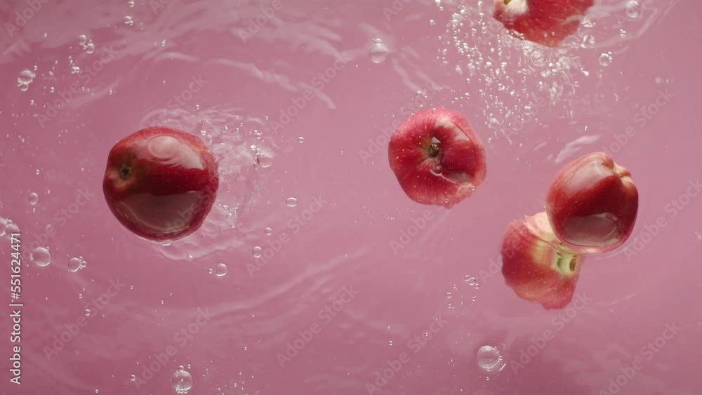 Falling apple in clear water. From above slow motion static shot of ...
