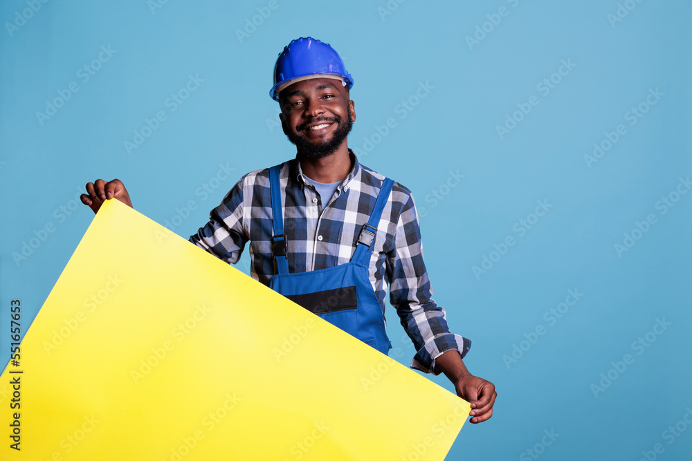 Relaxed construction worker with protective helmet presenting a panel ...
