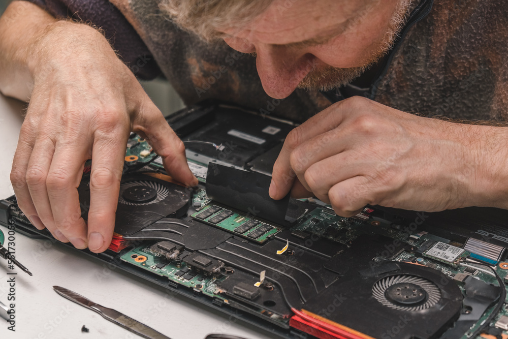 repairman checks laptop cooling system before disassembling, checking ...