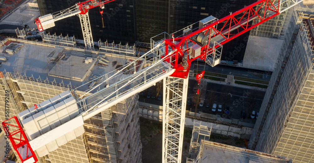 Aerial view of two red and white industrial tower crane operating in ...