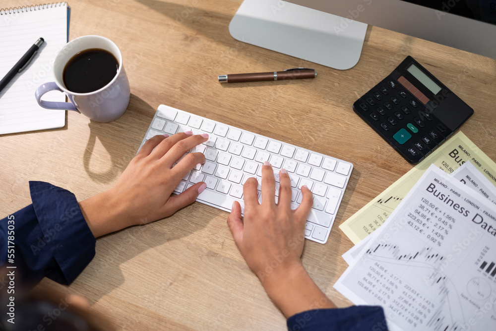 Woman types on the computer keyboard. High angle view. Desk with ...