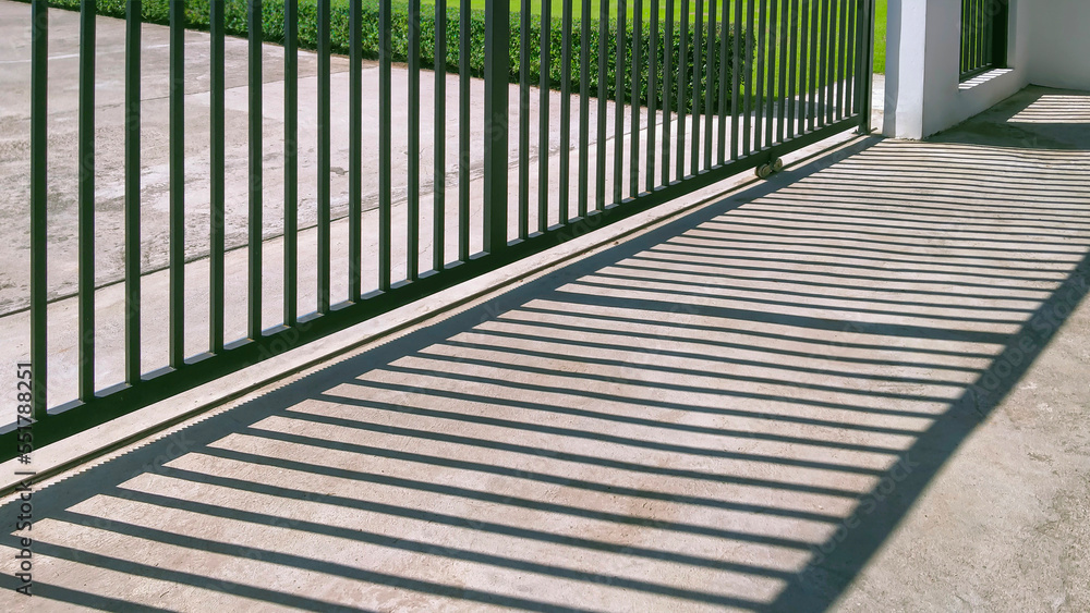 Sunlight and shadow on surface of automatic sliding metal fence gate in ...