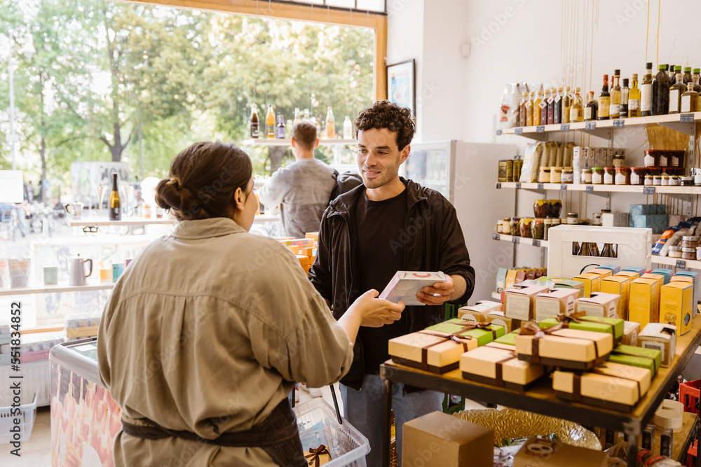 Male customer buying grocery while talking to female owner in shop ...