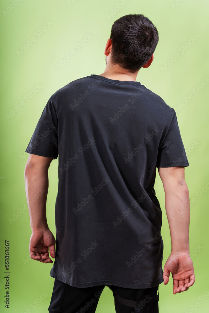 guy in a black t-shirt on a green background. the back of a man in a ...