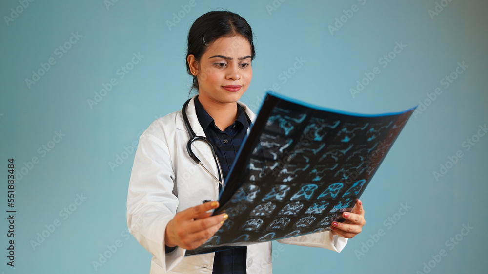 Portrait of a young female doctor examining patient's CT scan x-rays ...