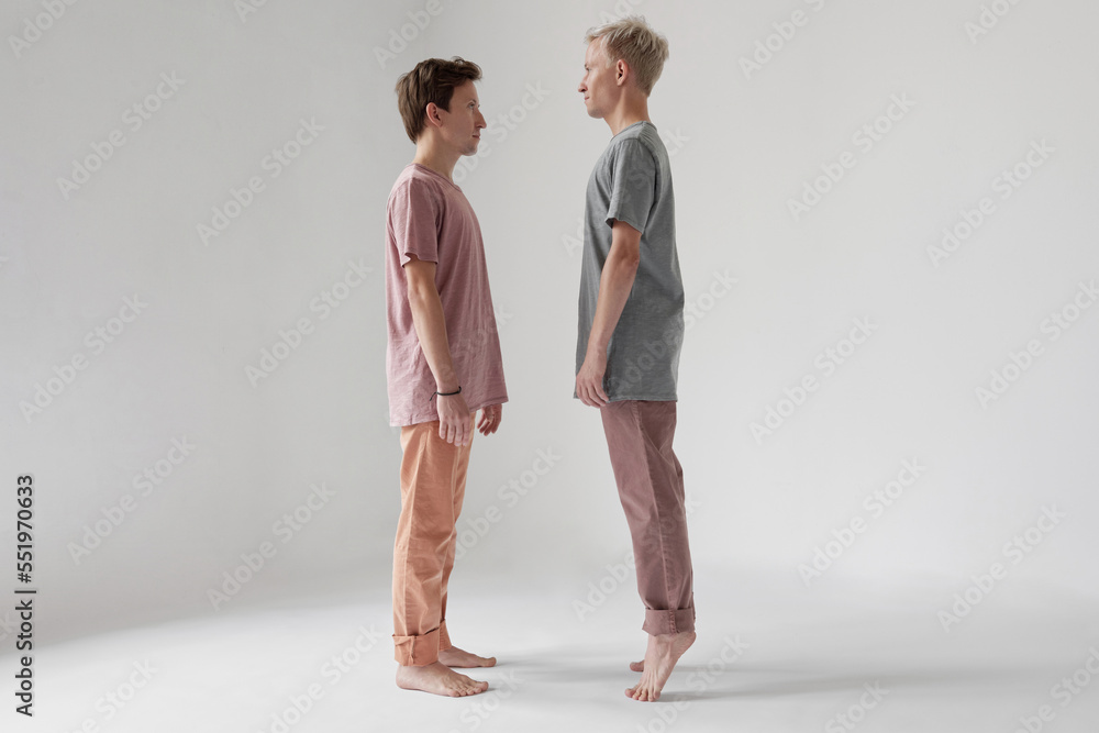 Horizontal shot of twins standing face to face with blond one standing ...