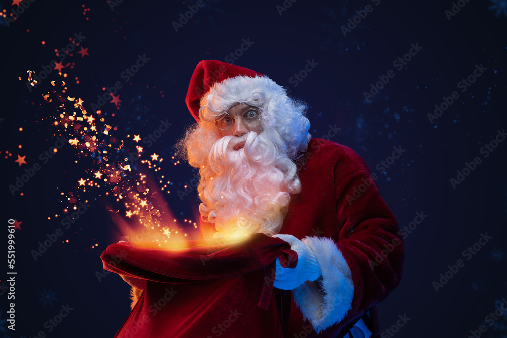 Shot of christmas santa holding bag with gifts staring at camera ...