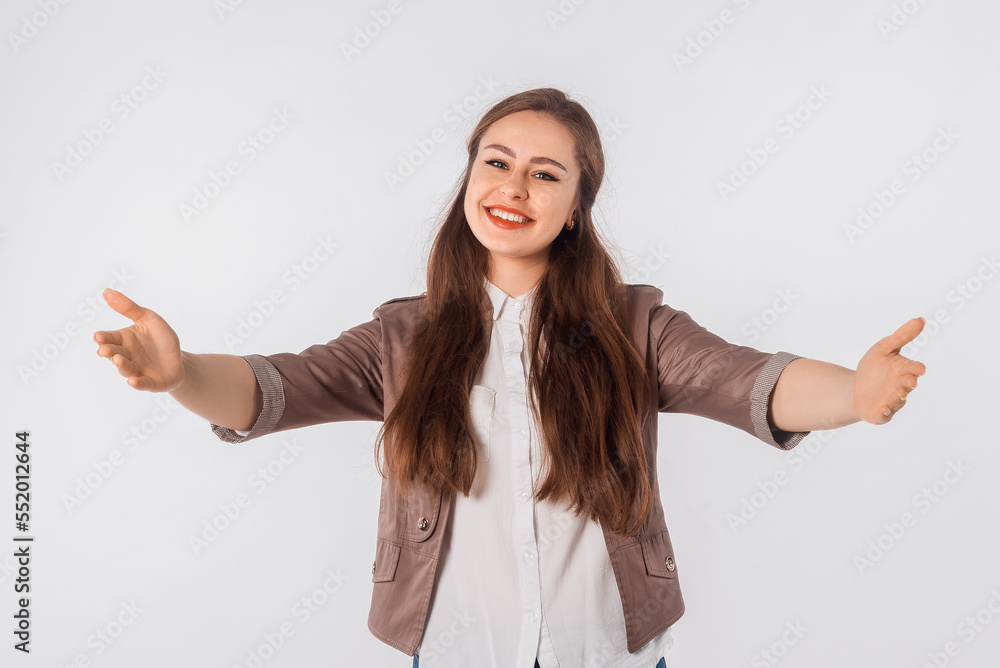 Portrait of young friendly woman standing against white studio ...