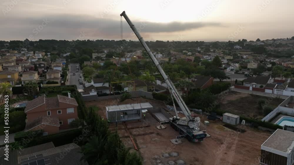 Modern modular home framework suspended by crane lift on construction ...