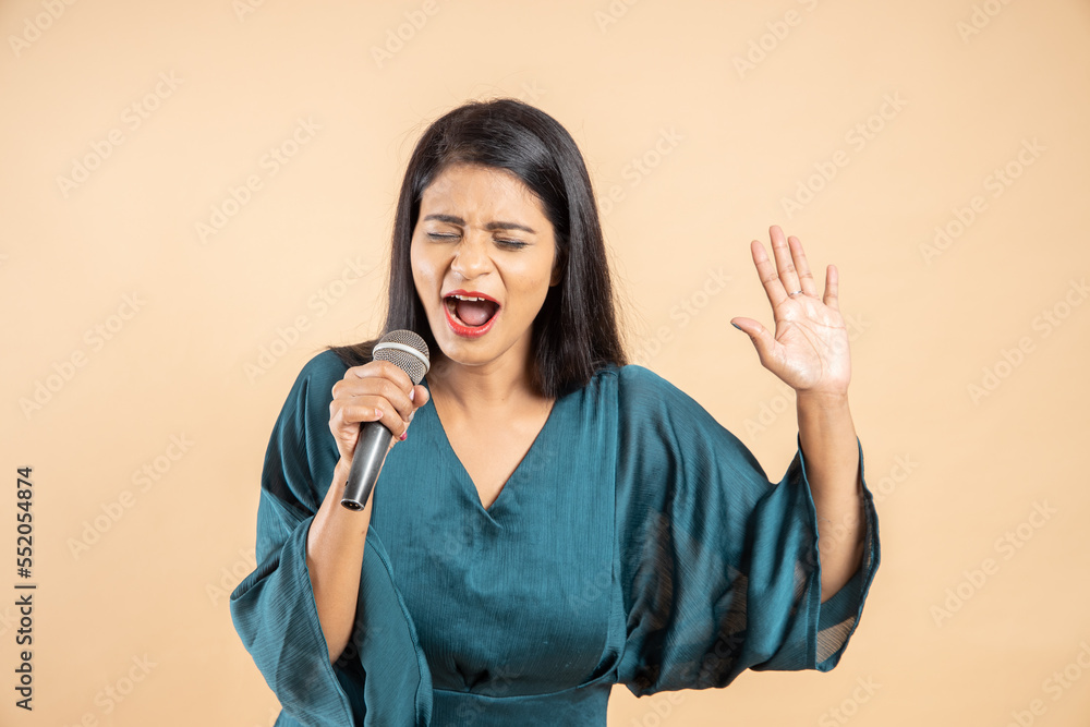 Beautiful young indian girl singer holding mic singing song isolated ...