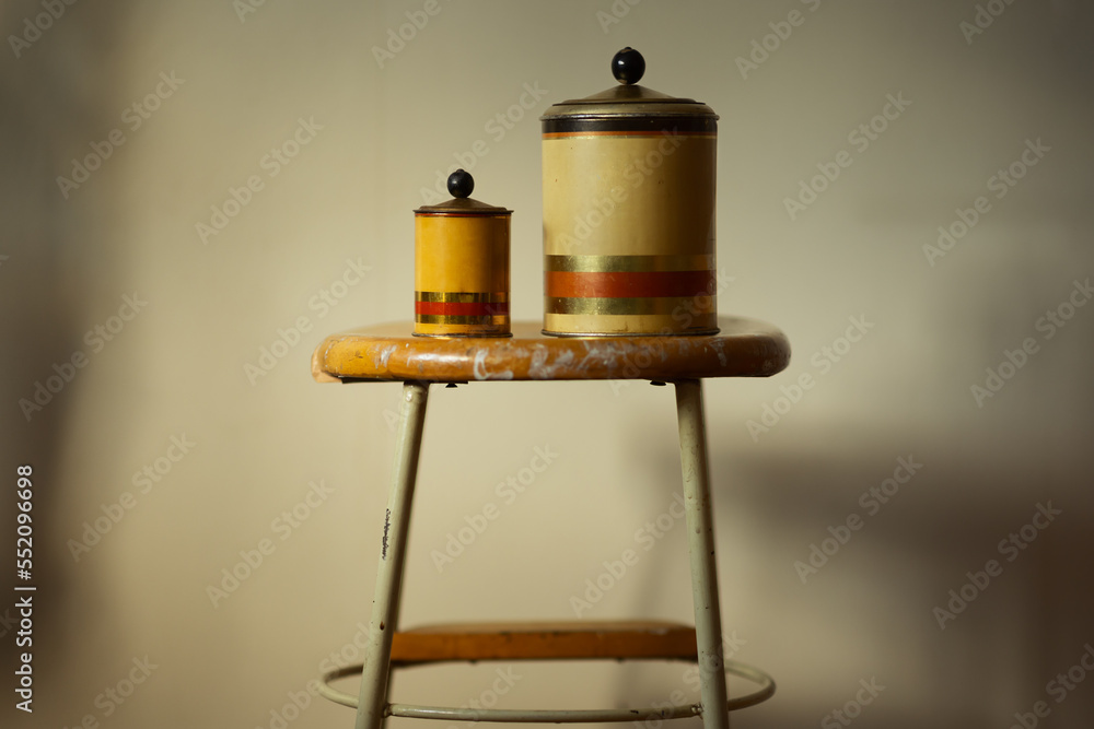 Two vintage jars standing on a vintage stool in a dramatic light ...
